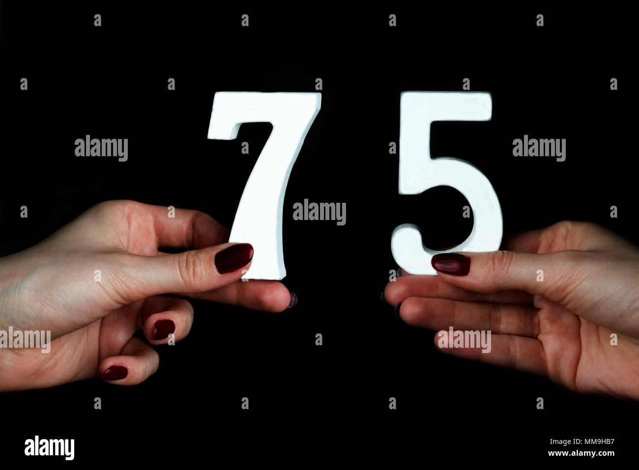 On a black background, female hand with numbers seventy-five Stock ...