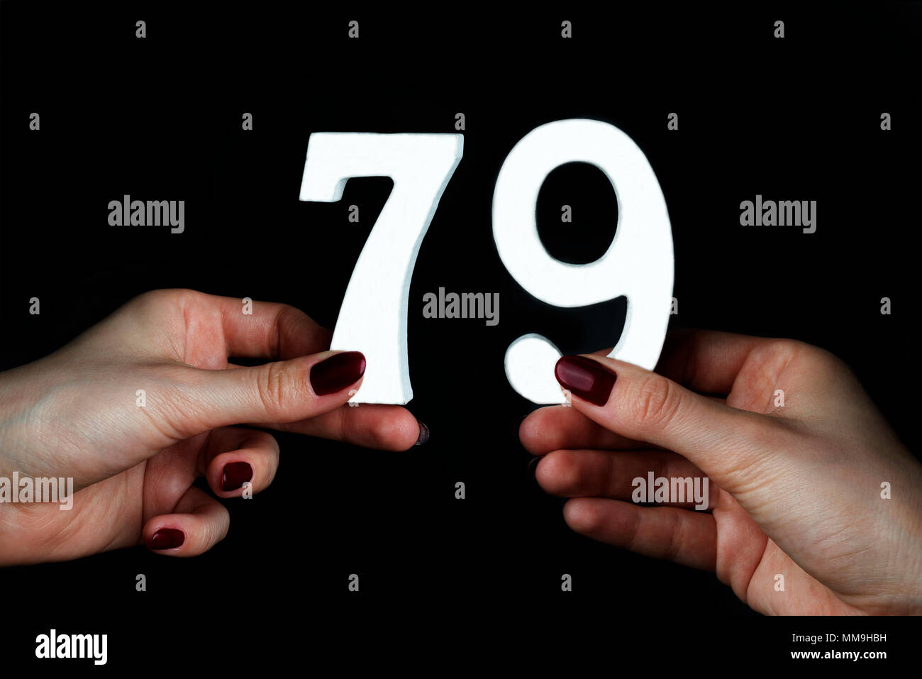 On a black background, female hand with numbers seventy-nine Stock ...