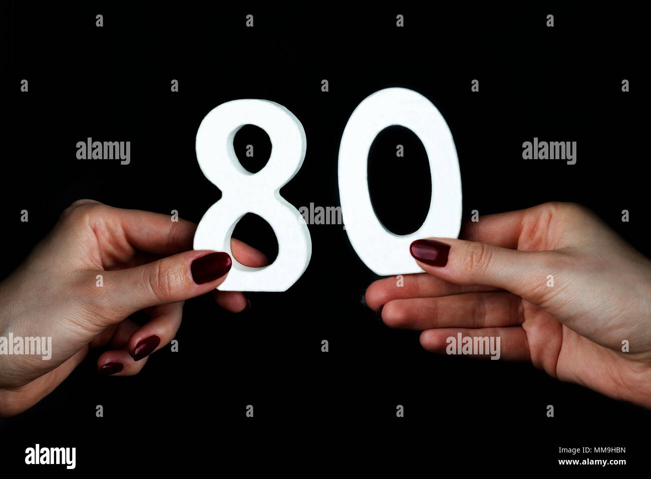 On a black background, female hand with numbers eighty Stock Photo - Alamy