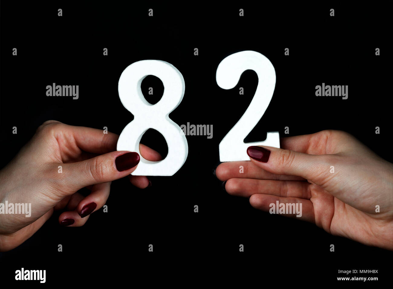 On a black background, female hand with numbers eighty-two Stock Photo ...