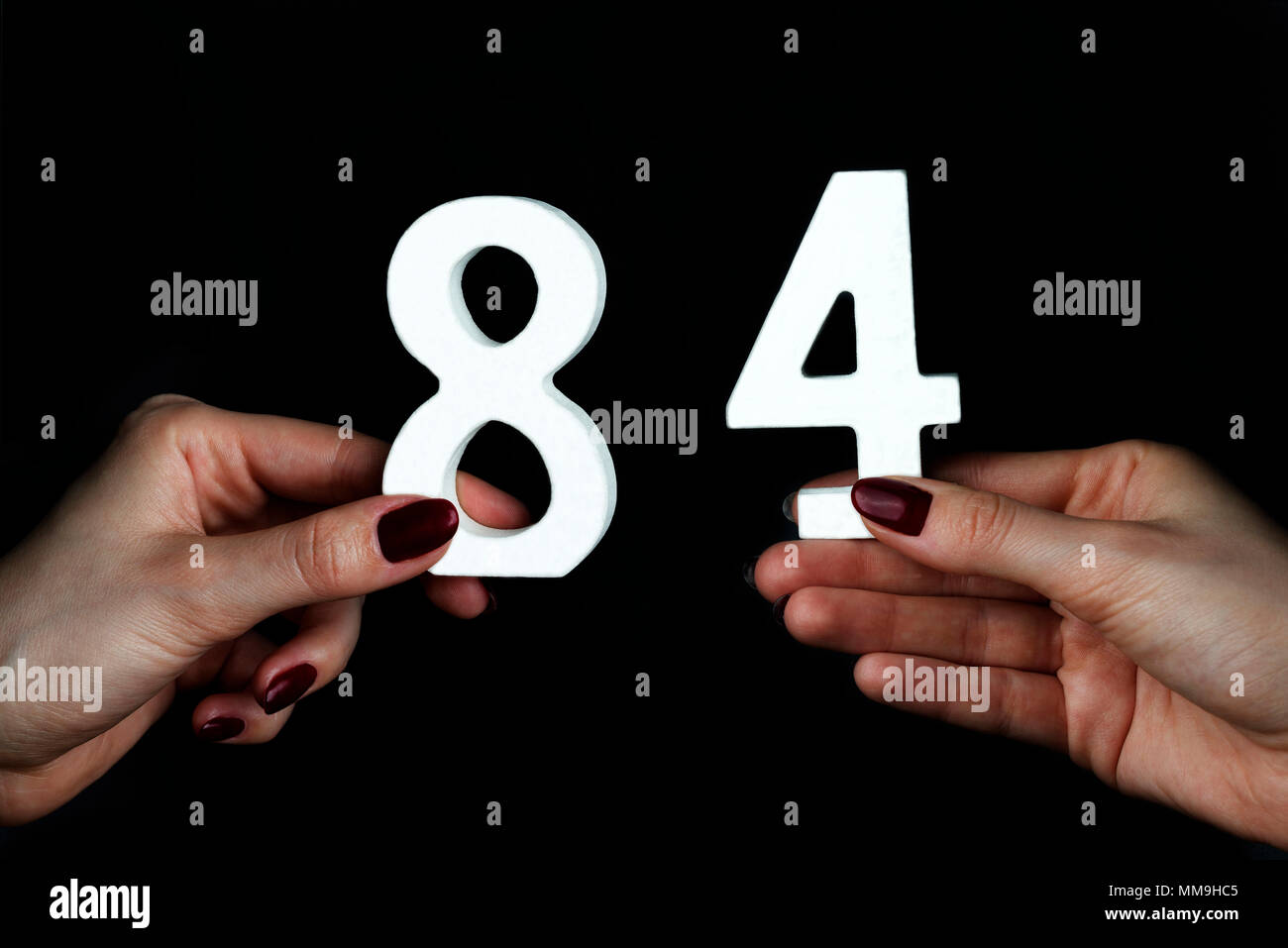 On a black background, female hand with numbers eighty-four Stock Photo ...