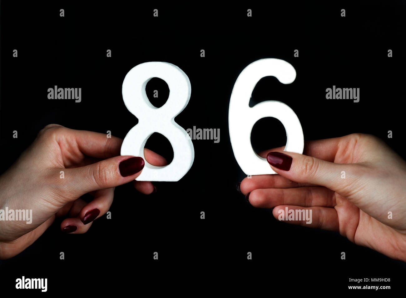 On a black background, female hand with numbers eighty-six Stock Photo ...