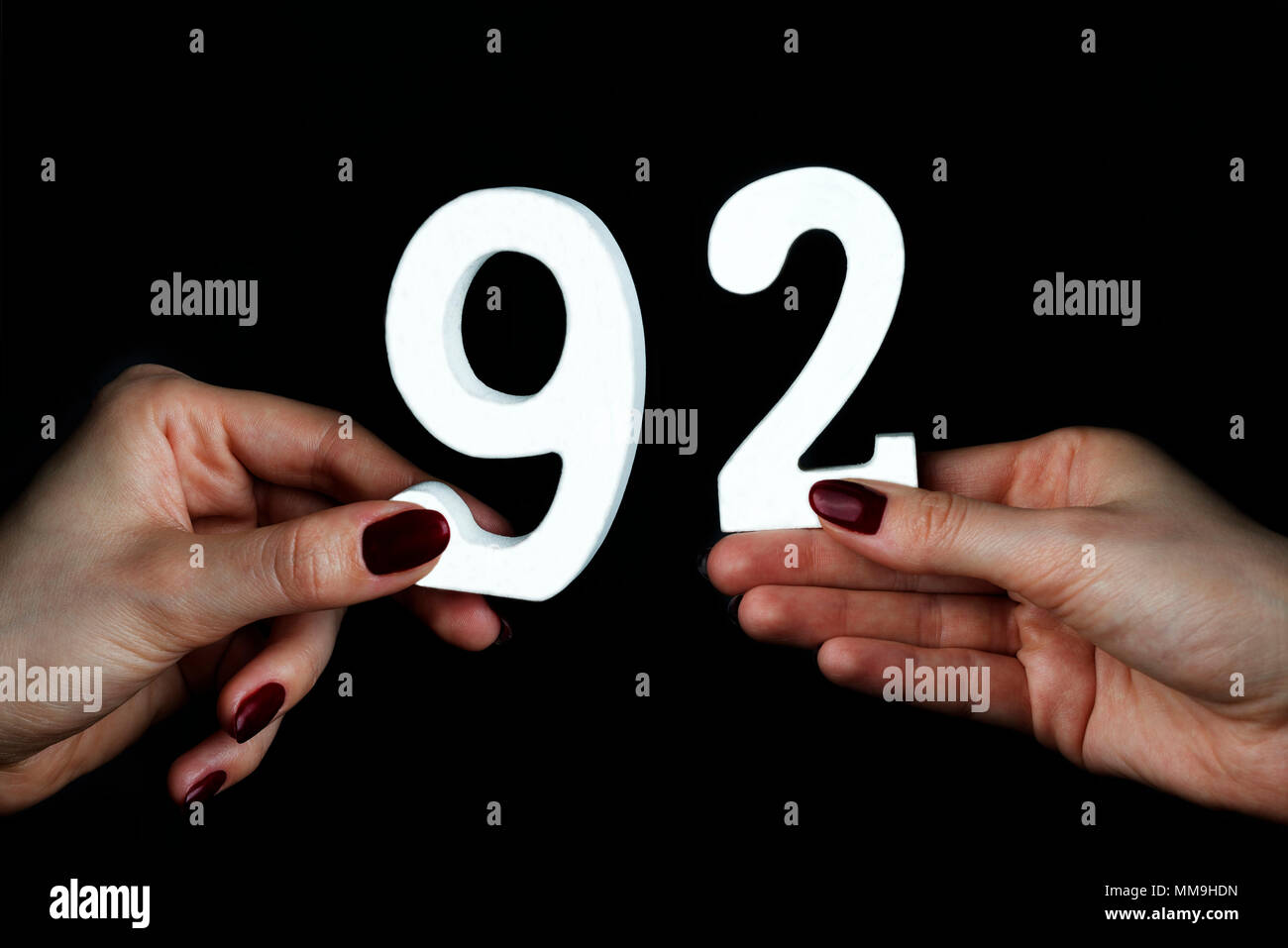 On a black background, female hand with numbers ninety-two Stock Photo ...