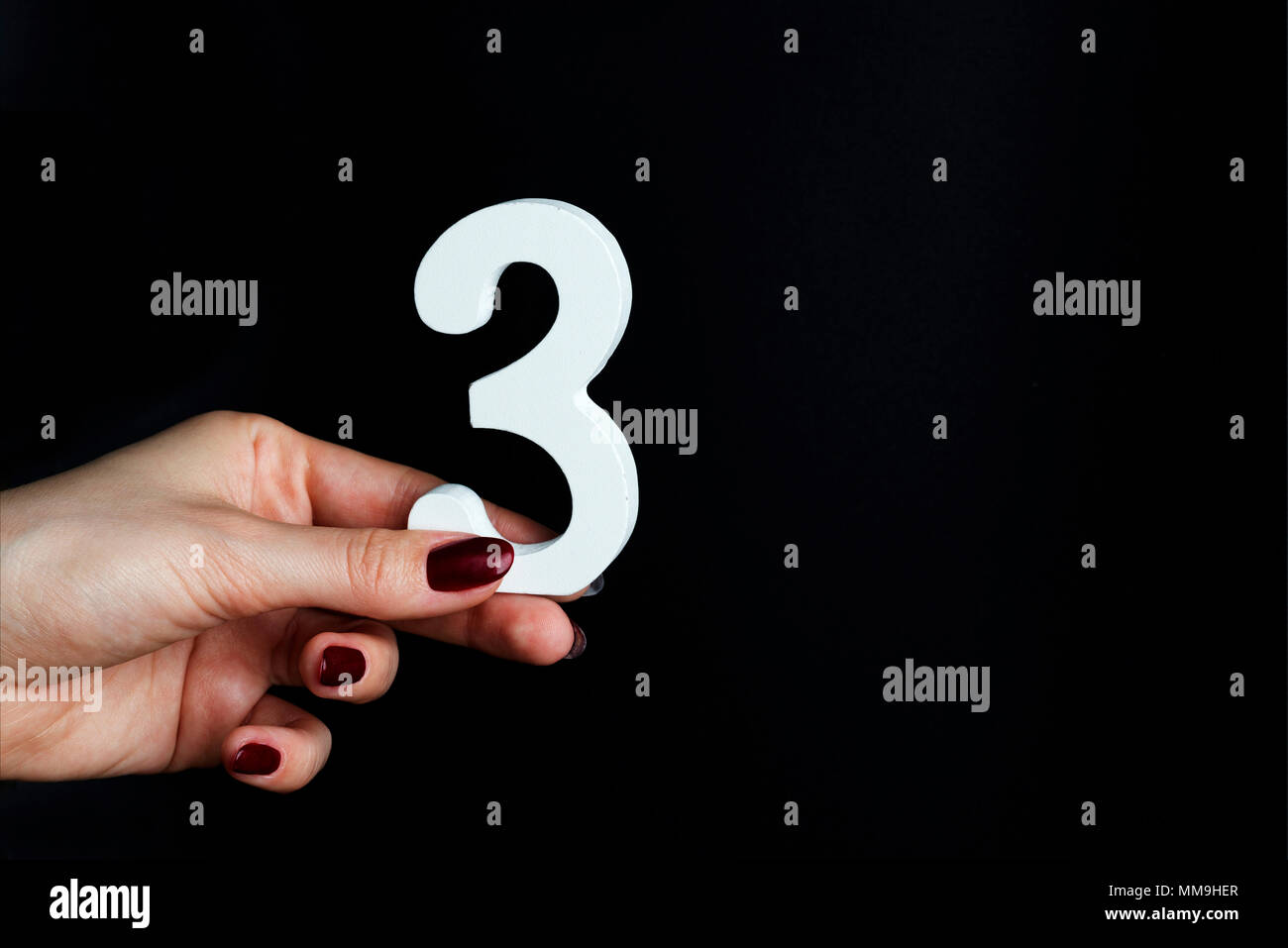 On a black background, female hand with number three Stock Photo - Alamy