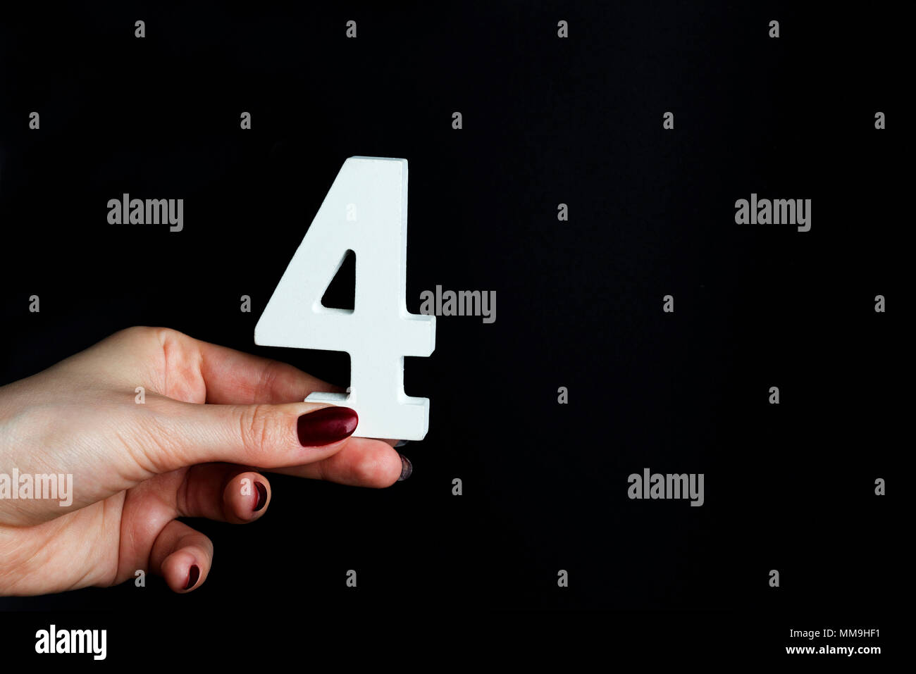On a black background, female hand with number four Stock Photo - Alamy