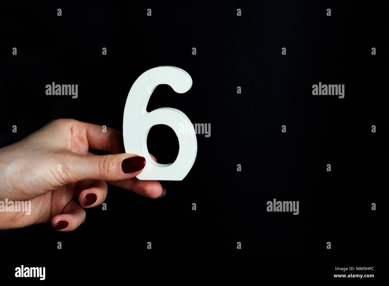 On a black background, female hand with number six Stock Photo - Alamy