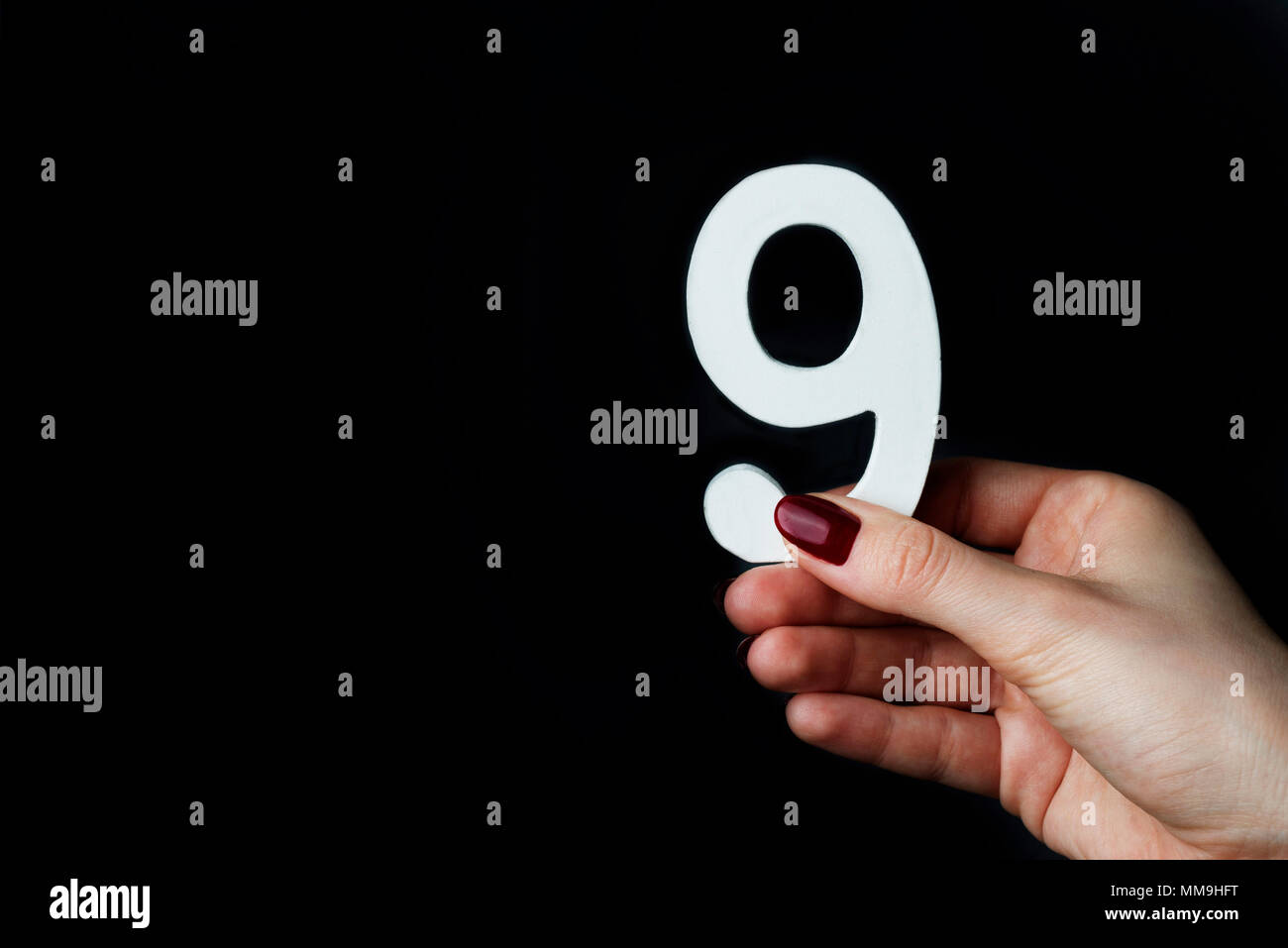 On a black background, female hand with number nine Stock Photo - Alamy