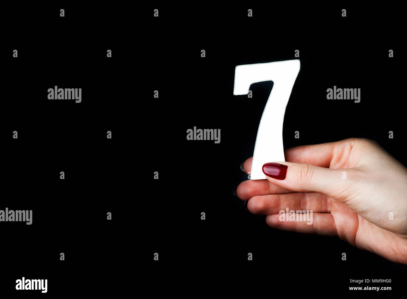 On a black background, female hand with number seven Stock Photo - Alamy