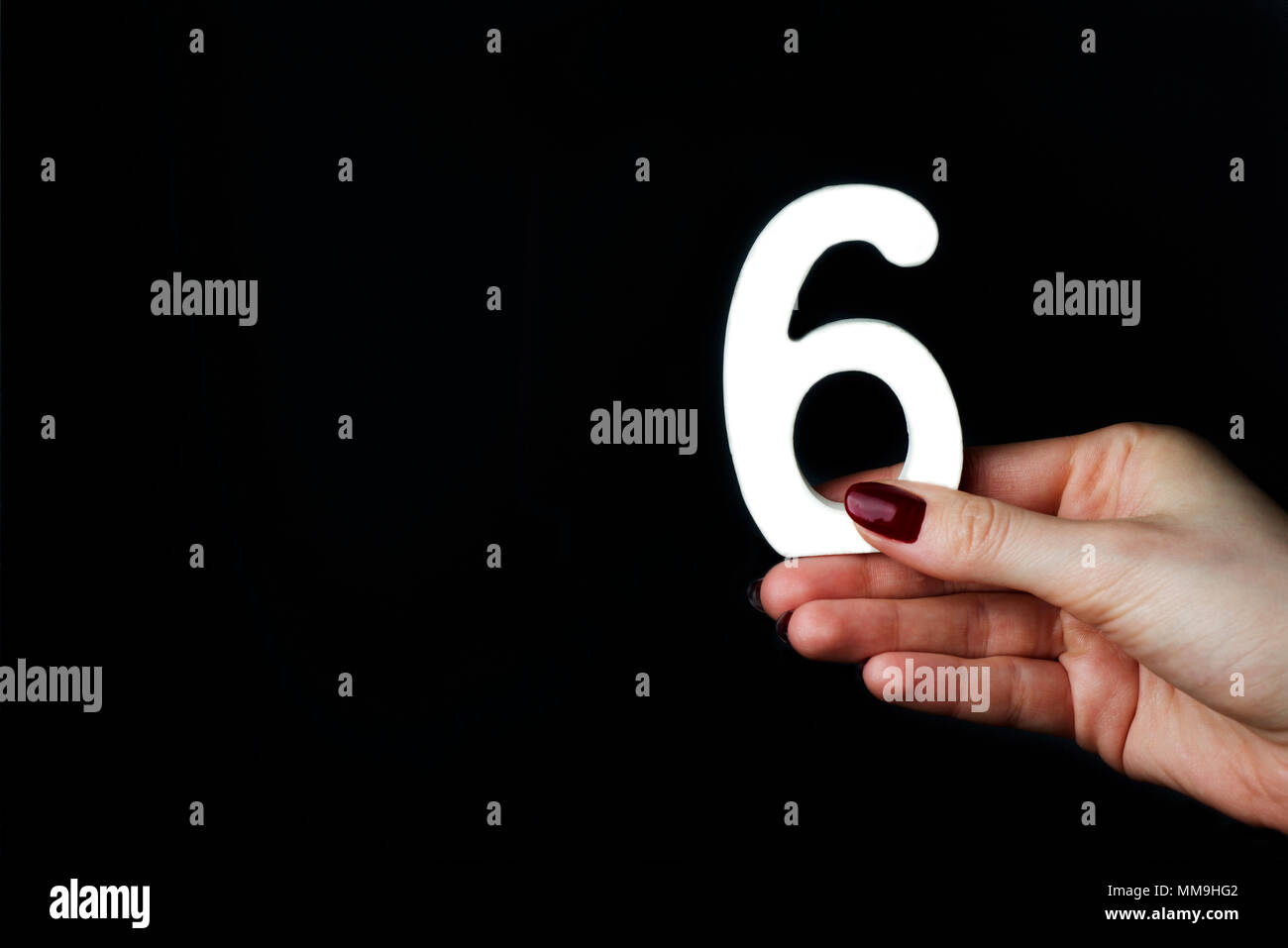 On a black background, female hand with number six Stock Photo - Alamy