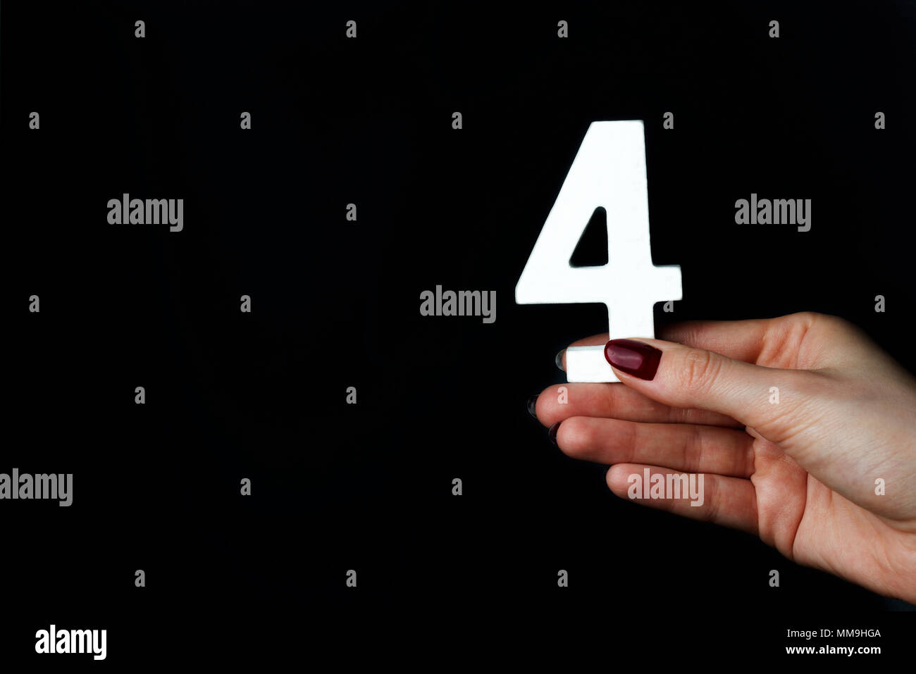 On a black background, female hand with number four Stock Photo - Alamy