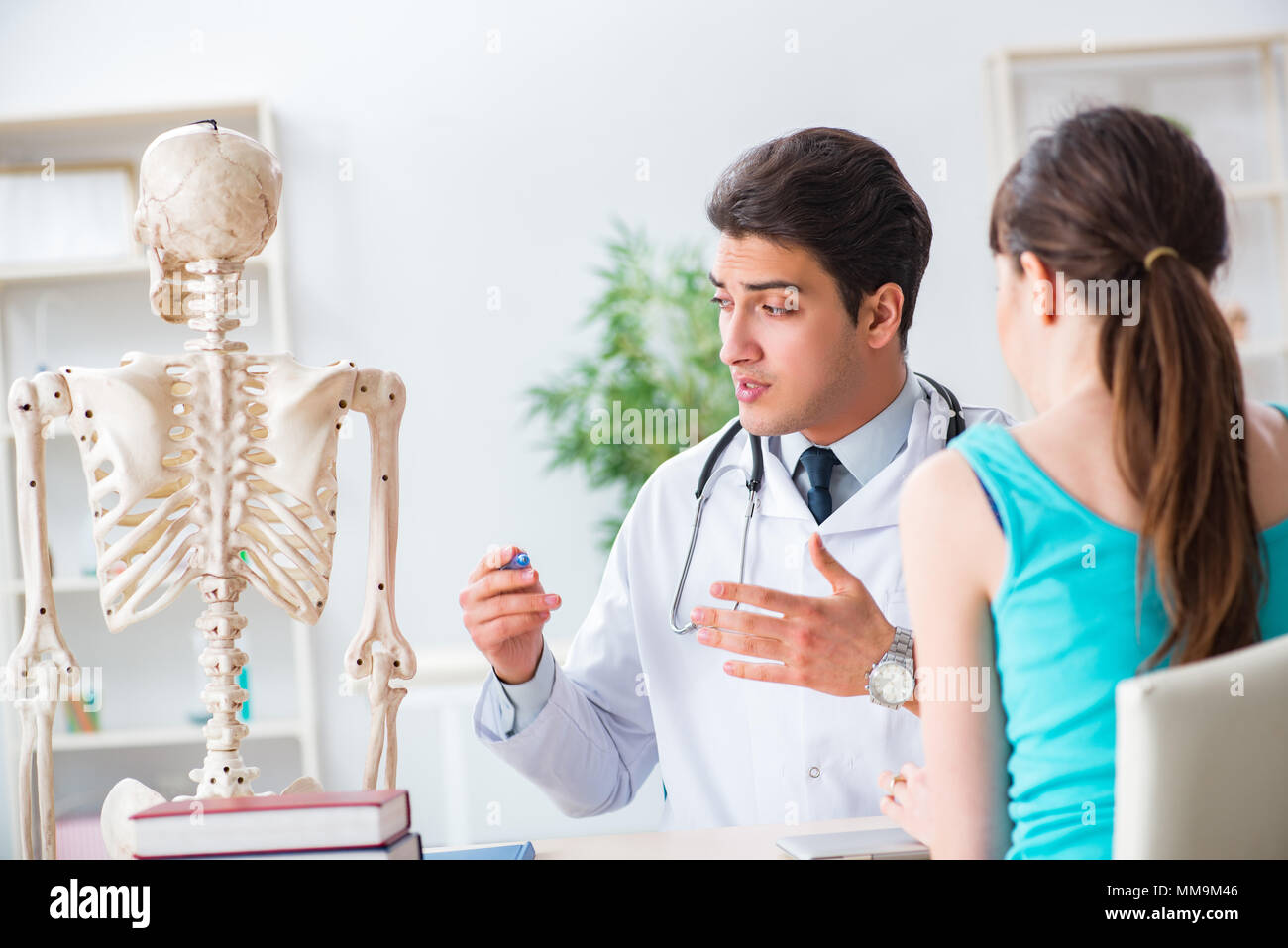 Doctor showing type of injury on skeleton to patient Stock Photo - Alamy