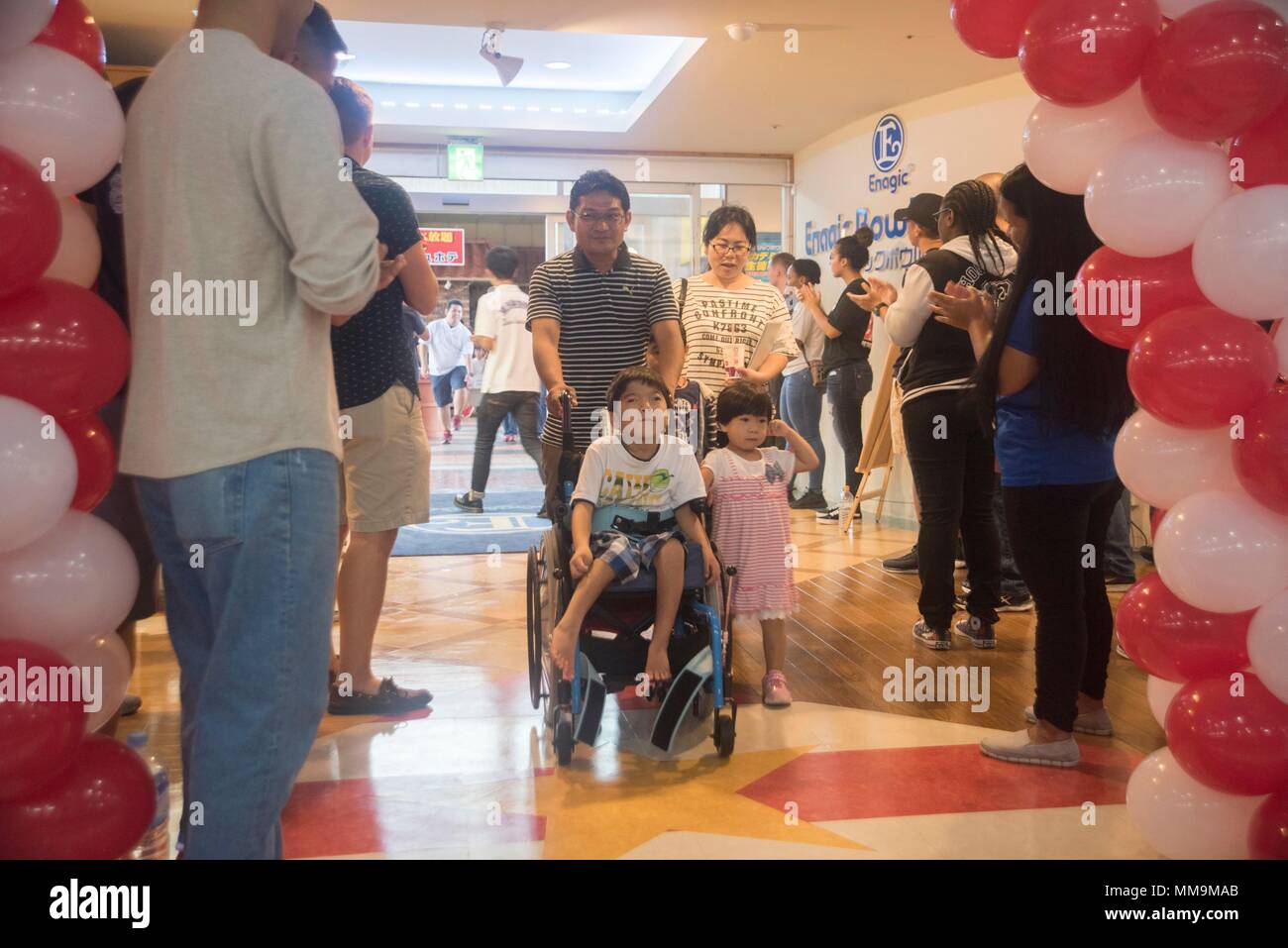 Families and participants arrive through an arch of balloons while ...