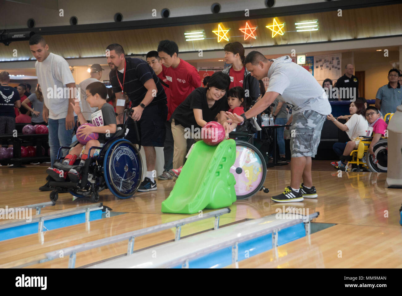 Family members and volunteers help Riko, bowling participant, get a ...
