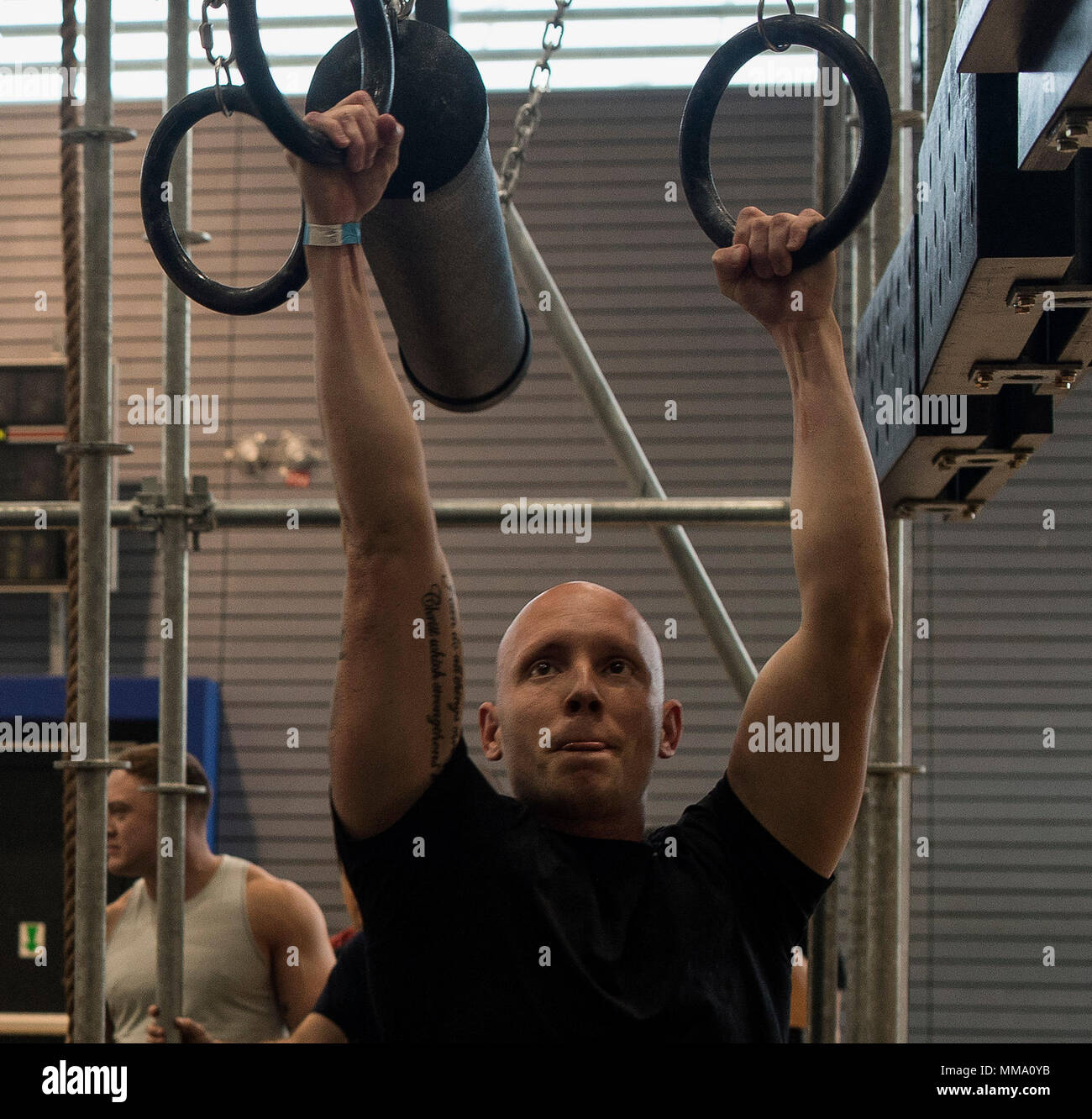 A U.S. Airman hangs from rings while attempting the battering ram ...