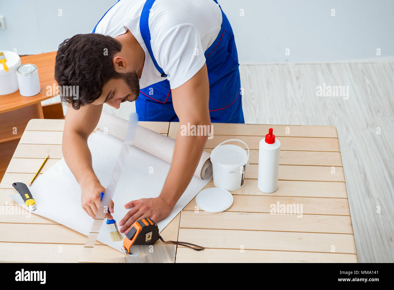 Worker working on wallpaper during refurbishment Stock Photo - Alamy