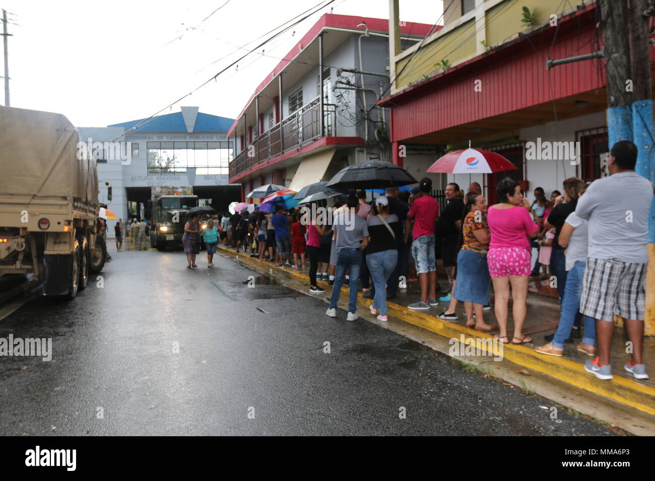 Residents of Florida, Puerto Rico, wait in line while soldiers assigned ...
