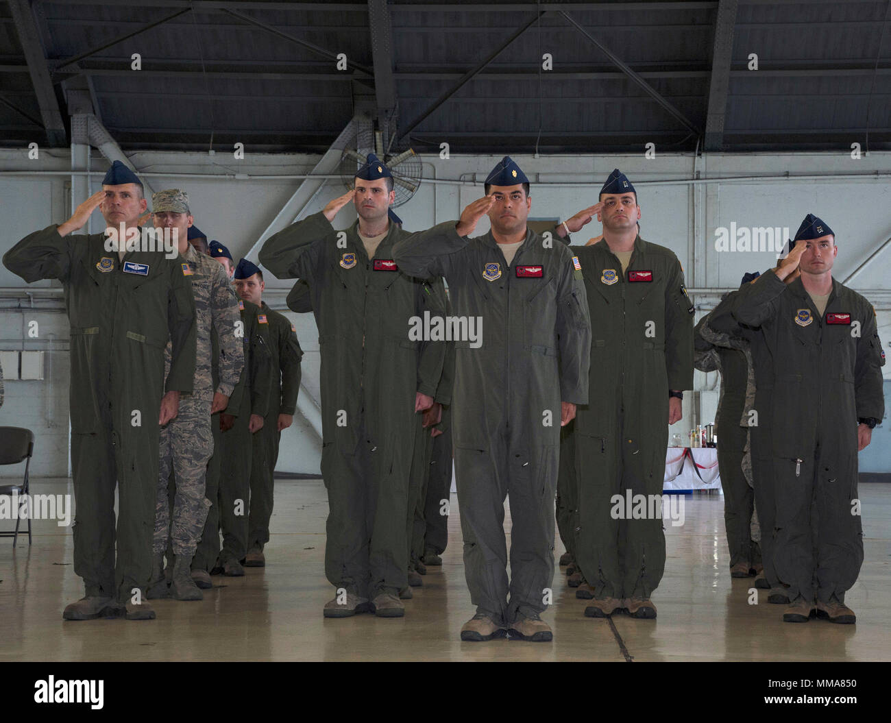 U.S. Air Force Airmen salute during the singing of the National Anthem ...
