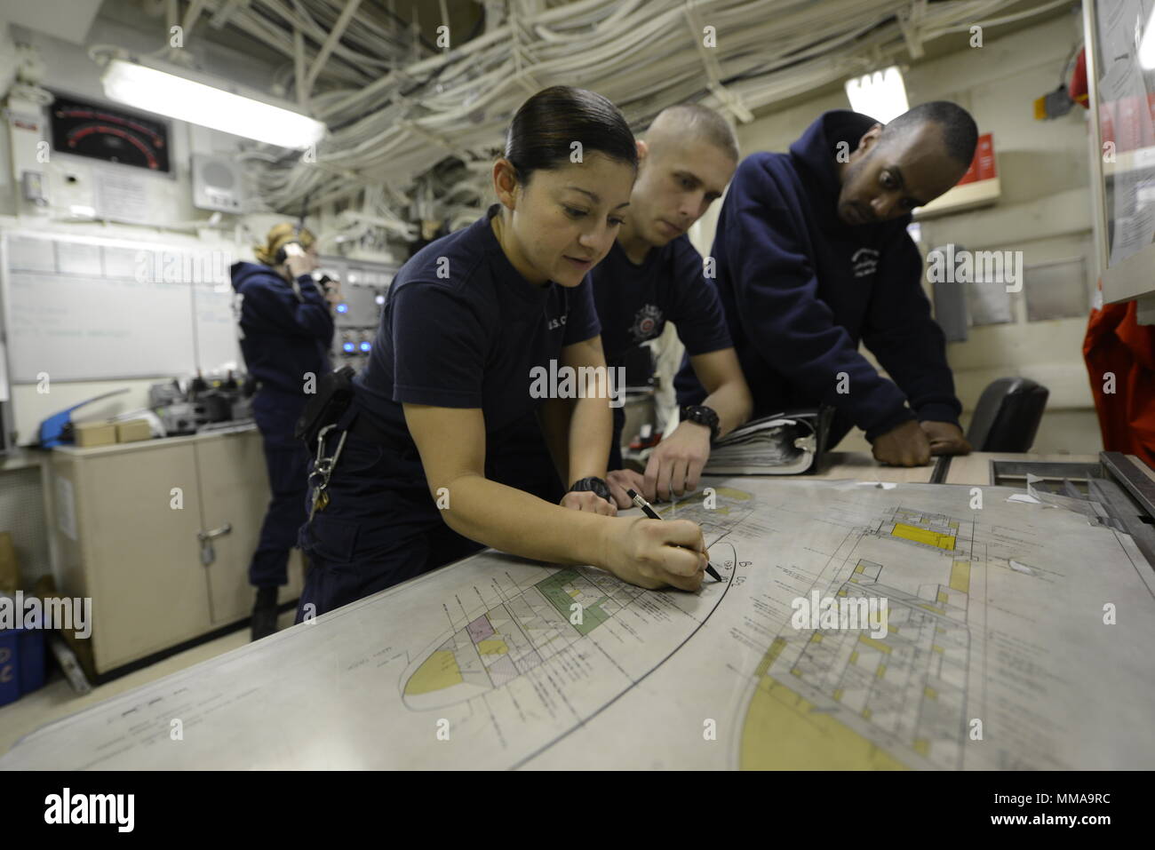 Coast Guard Fireman Candida Imhoff (center) writes on a damage control ...