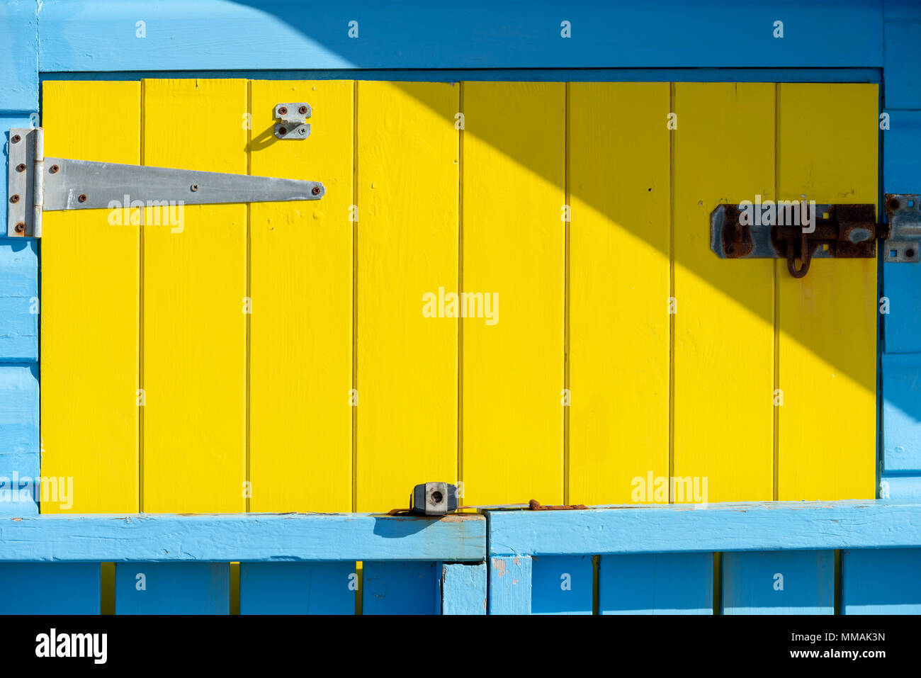 A brightly colourful blue and yellow beach hut on the beach at ...