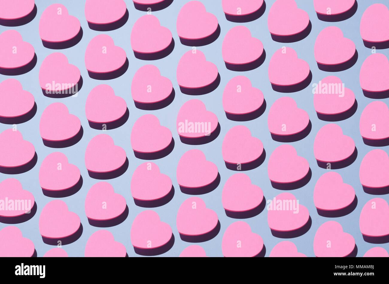 Pink heart shaped sticky notes organized in a row over blue background ...