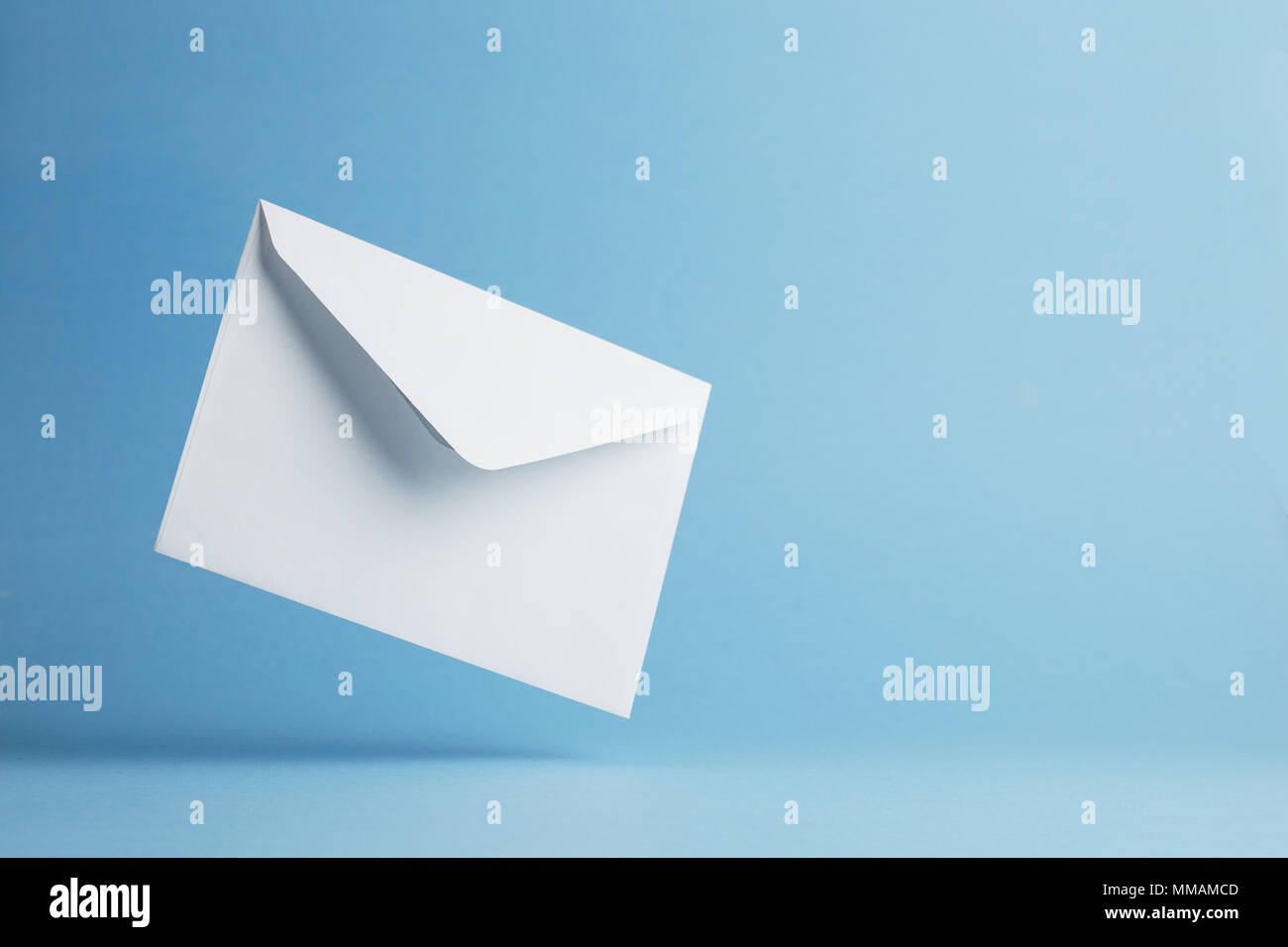 Envelope falling on the ground, blue background with negative space ...