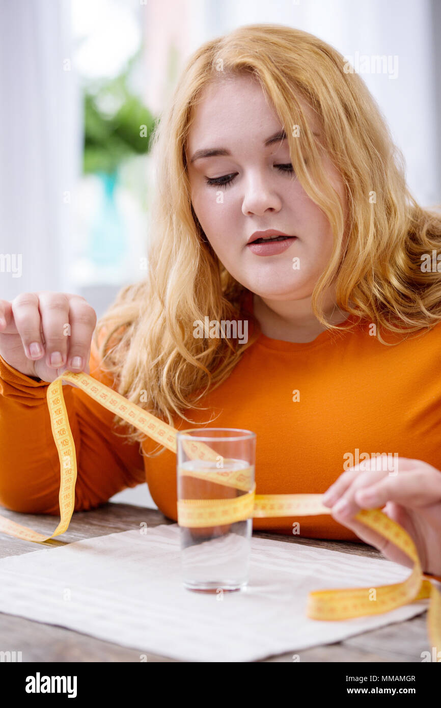 Concentrated woman holding a measuring tape Stock Photo - Alamy