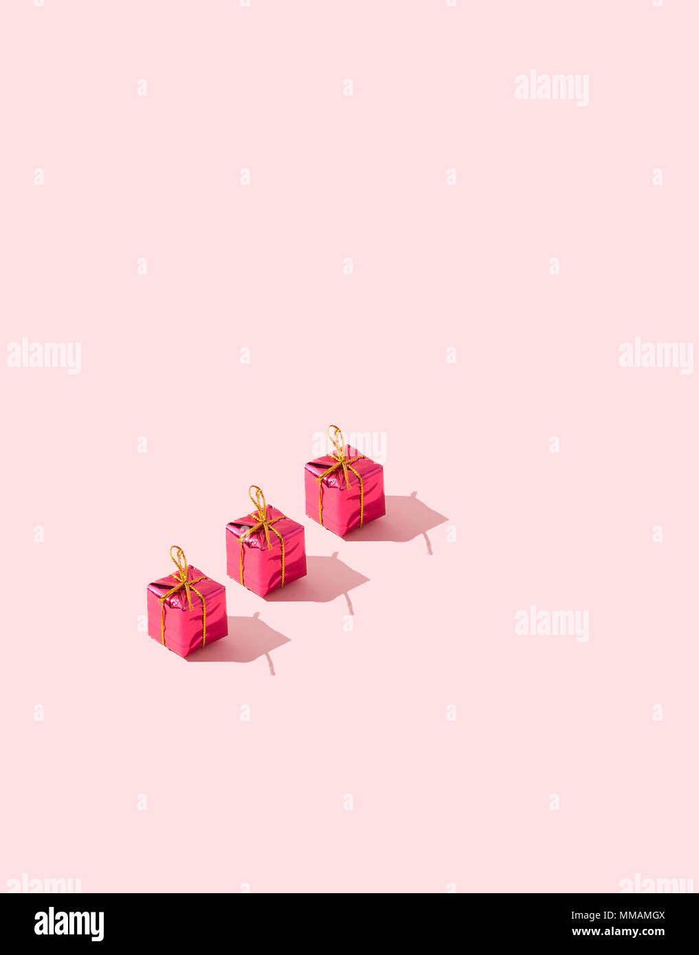 Three small gift boxes organized in a row over pink background Stock ...
