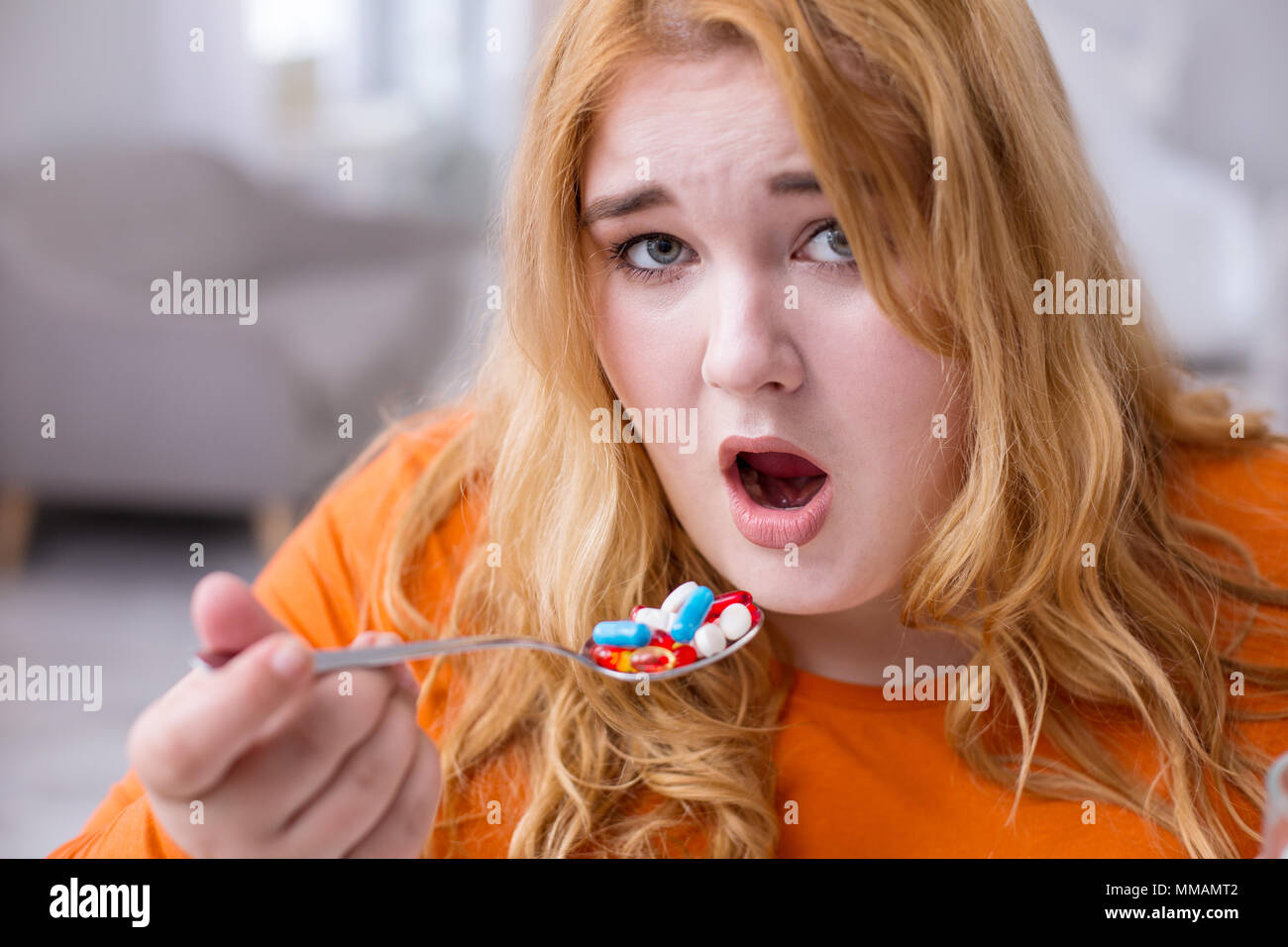 Miserable stout woman taking medications Stock Photo - Alamy
