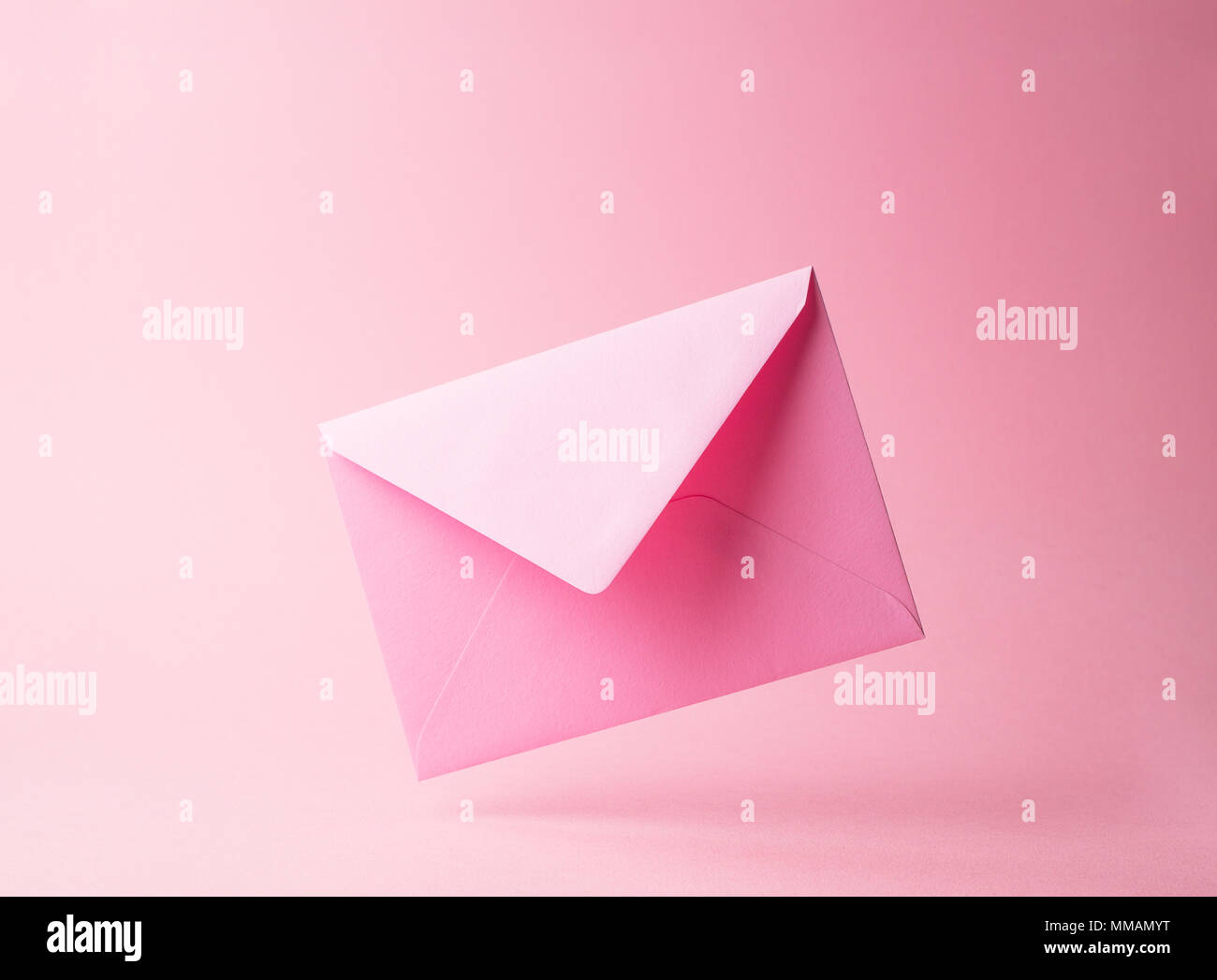 Pink envelope dropped over pink background Stock Photo - Alamy