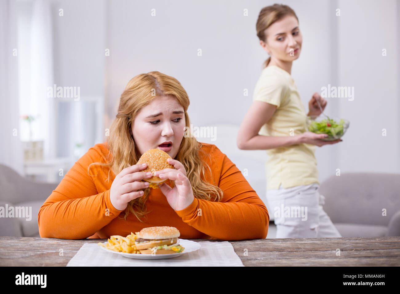 Sad stout woman eating a sandwich Stock Photo - Alamy