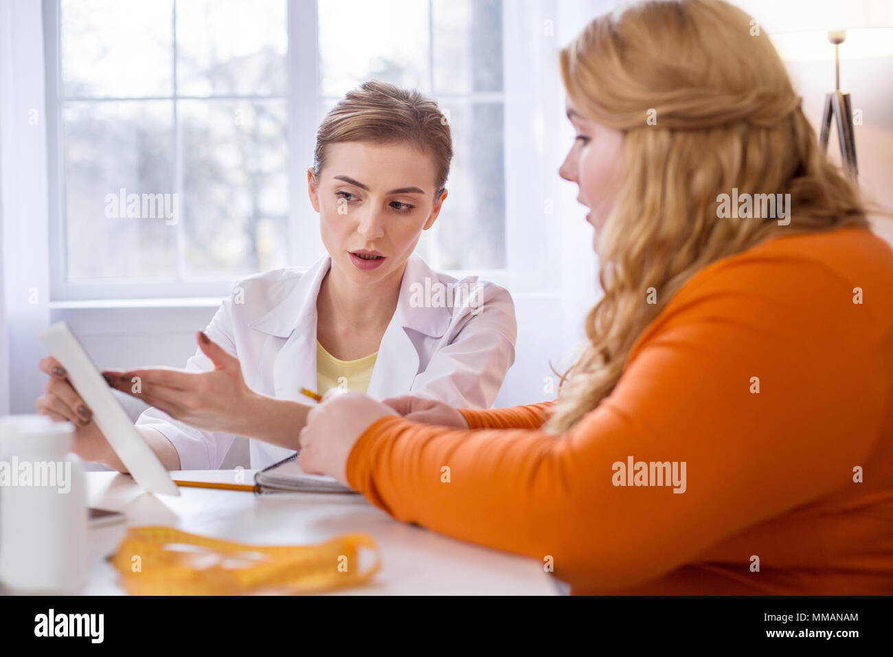 Determined skilled nutritionist talking with a stout woman Stock Photo ...