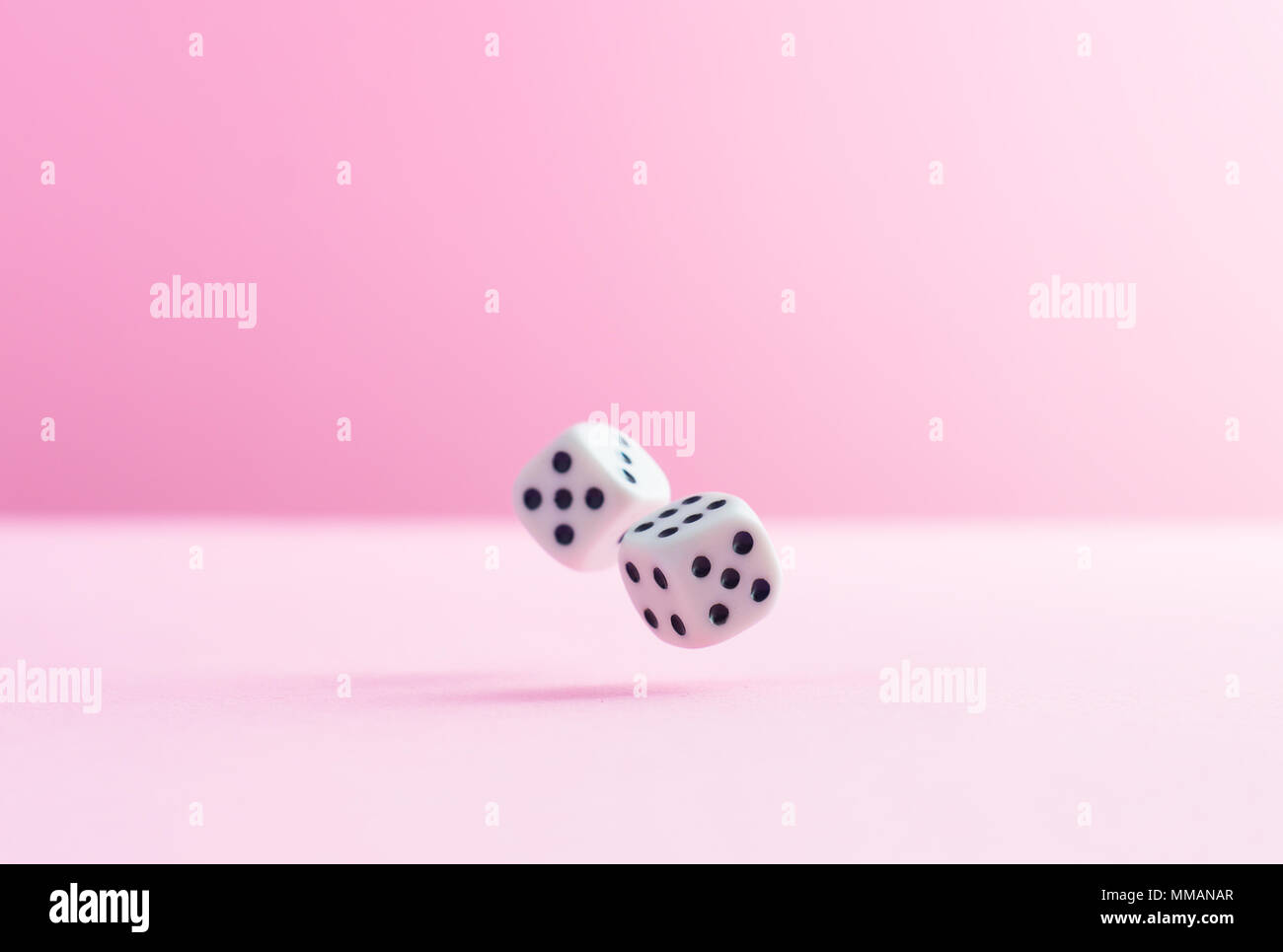 Two dice fall over pink background Stock Photo - Alamy