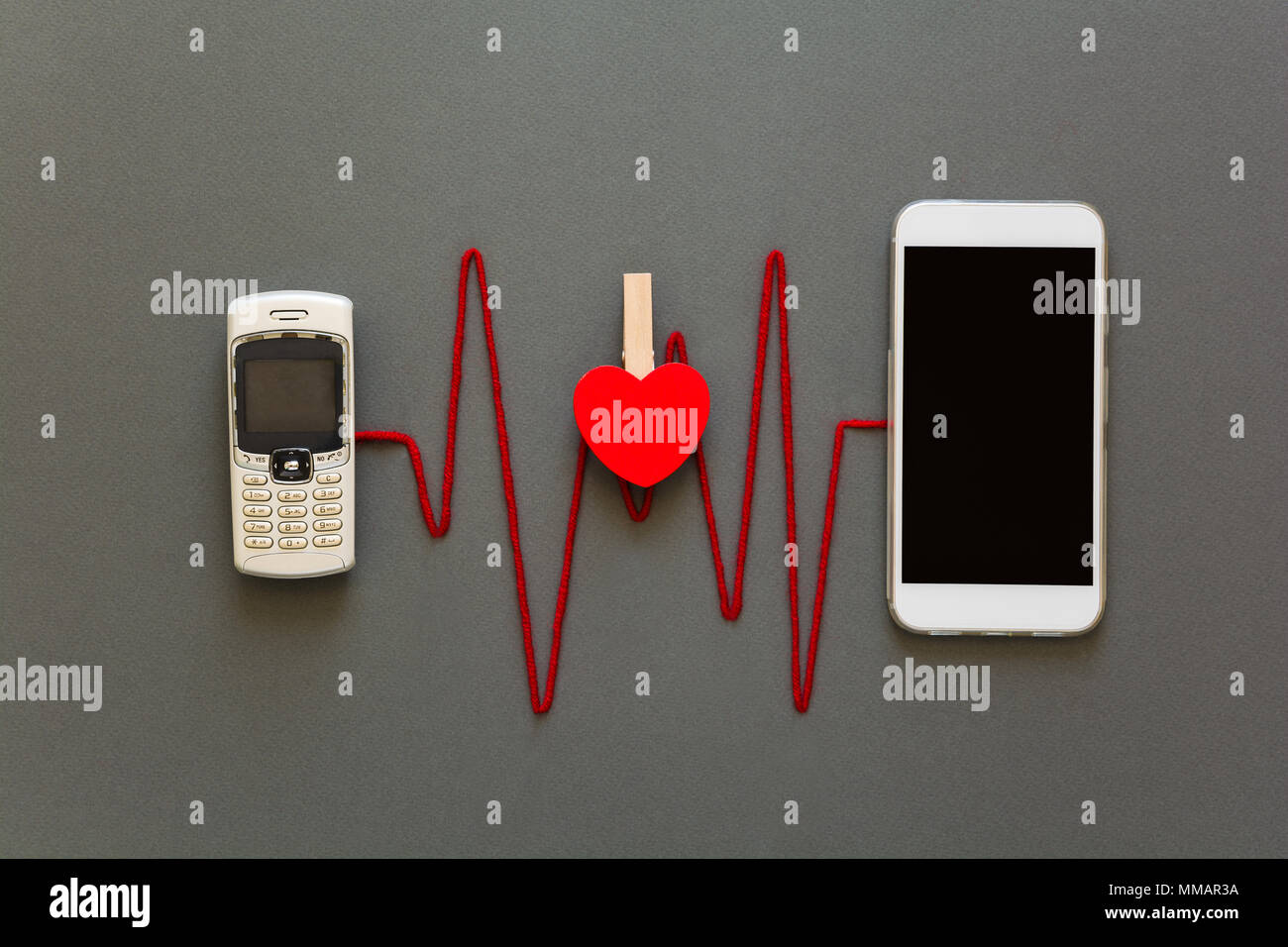 Old phone and new smartphone connected by red pulse laying on grey ...
