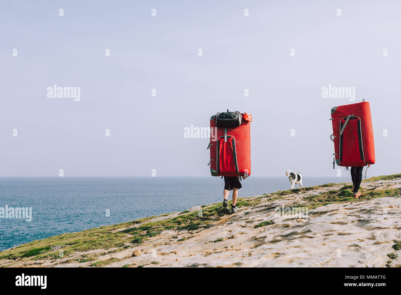Couple of climbers with dog hiking with crash pads on the back to climb ...