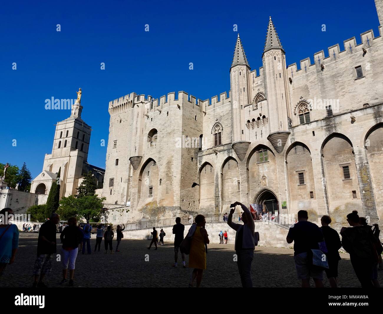 People in shadow in the late afternoon in front of the Pope’s Palace ...
