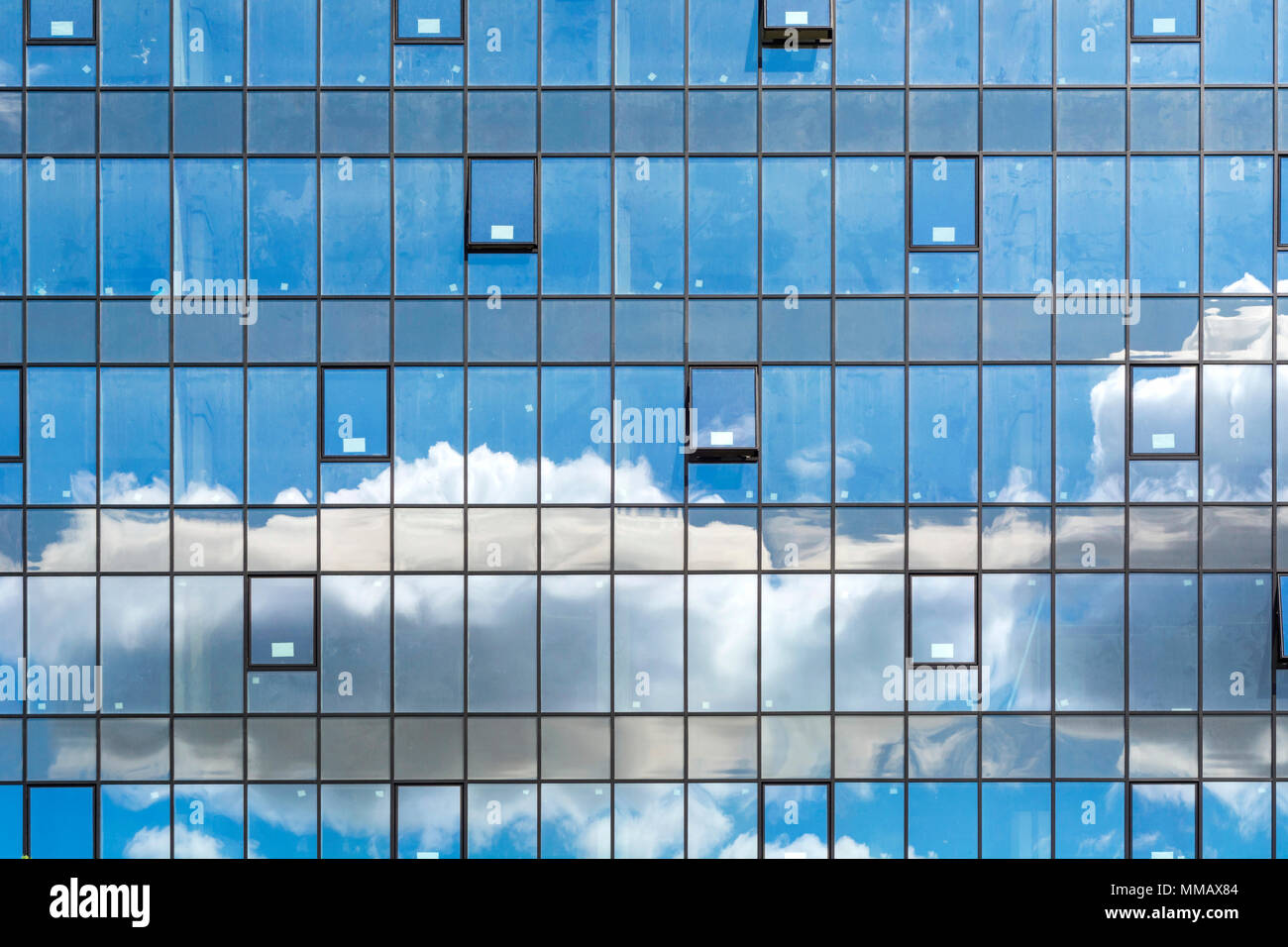 Cloudy sky reflected in the windows of modern office building. Urban ...
