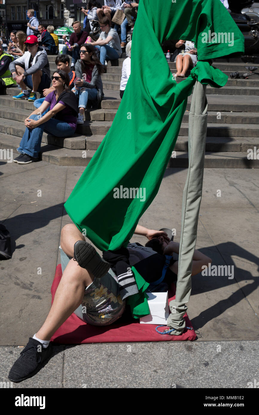 A street busker sleeps beneath his costume in Piccadilly Circus, on 9th ...