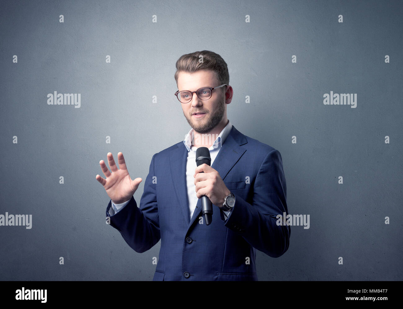 Businessman speaking into microphone with blue background Stock Photo ...