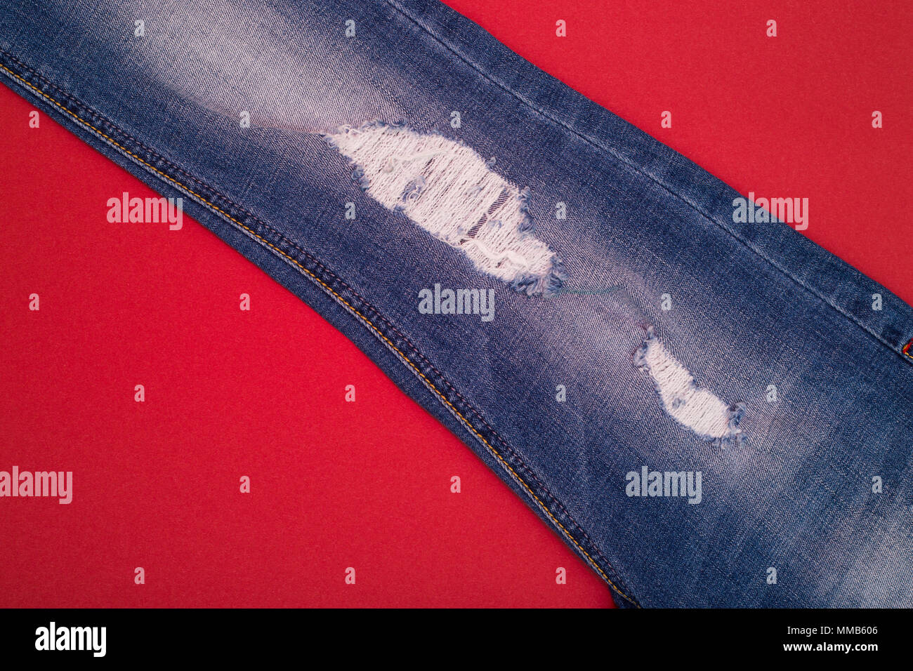 Ripped jeans light blue on a red background Stock Photo - Alamy
