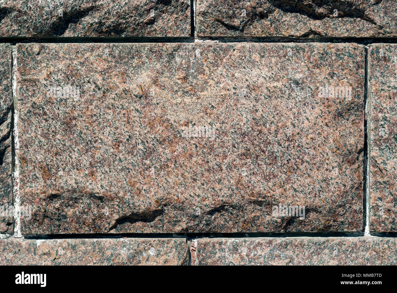 rough granite rectangular block in the composition of masonry wall ...