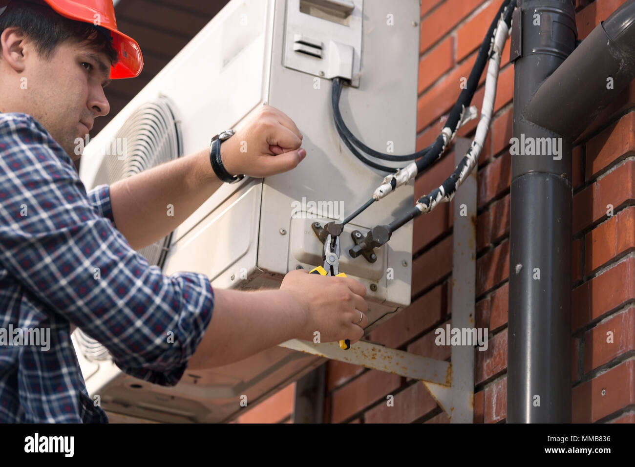 Closeup image of male repairman connecting air conditioner pipes and ...