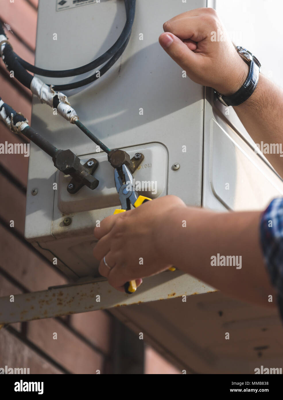 Closeup photo of male repairman fixing outdoor air conditioner unit ...