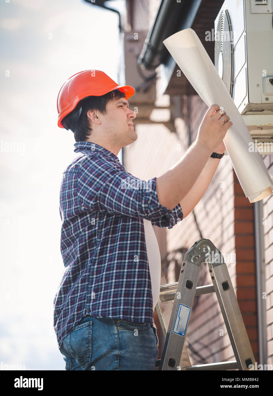 Portrait of male engineer looking blueprints of house air conditioning ...
