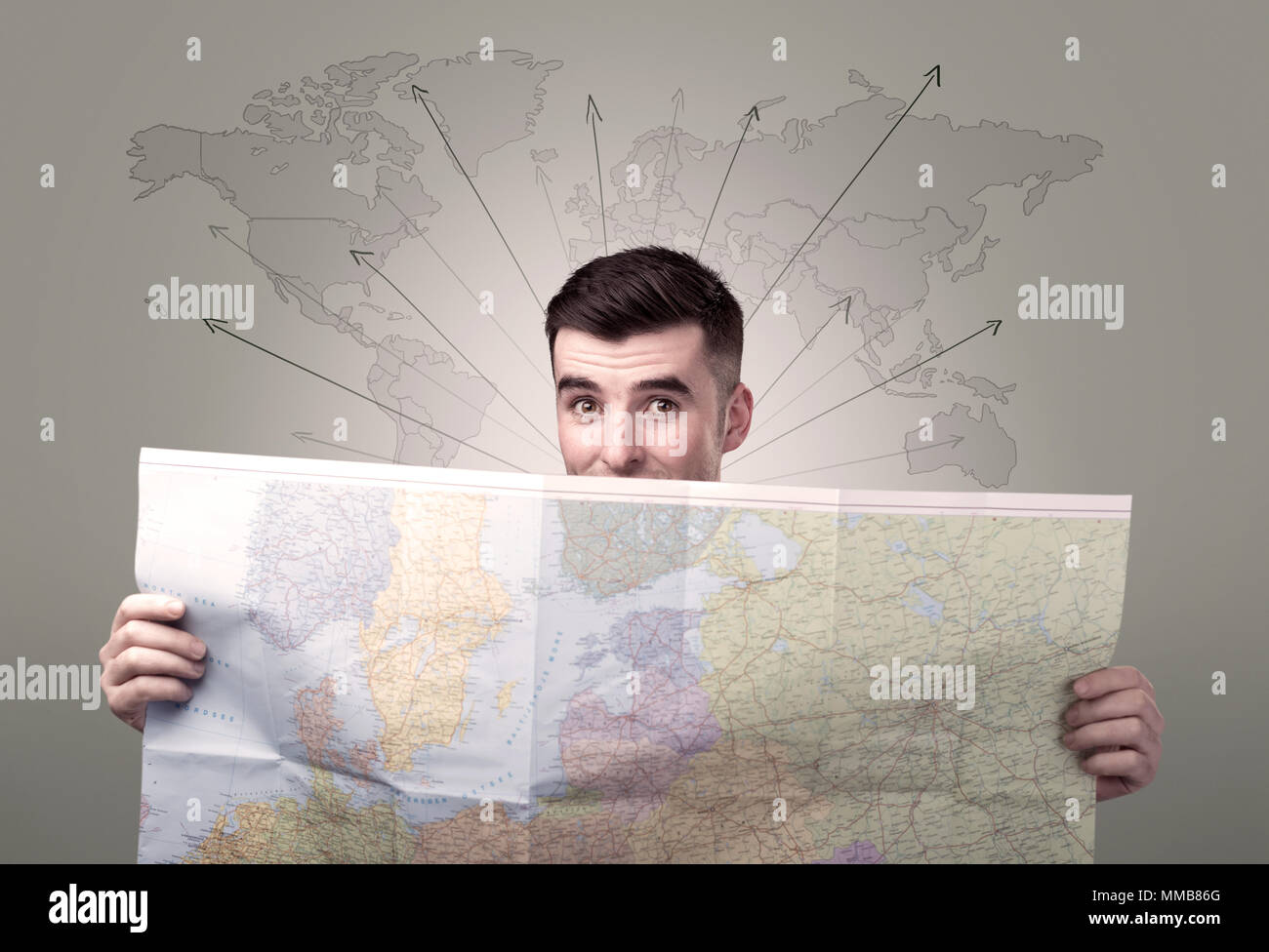 Handsome young man holding a map with world map and arrows behind him ...