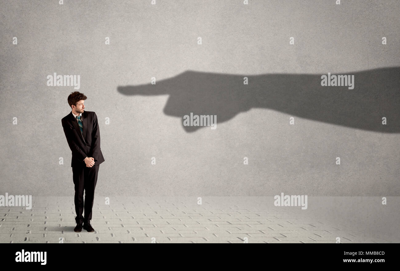 Business person looking at huge shadow hand pointing at him concept on ...