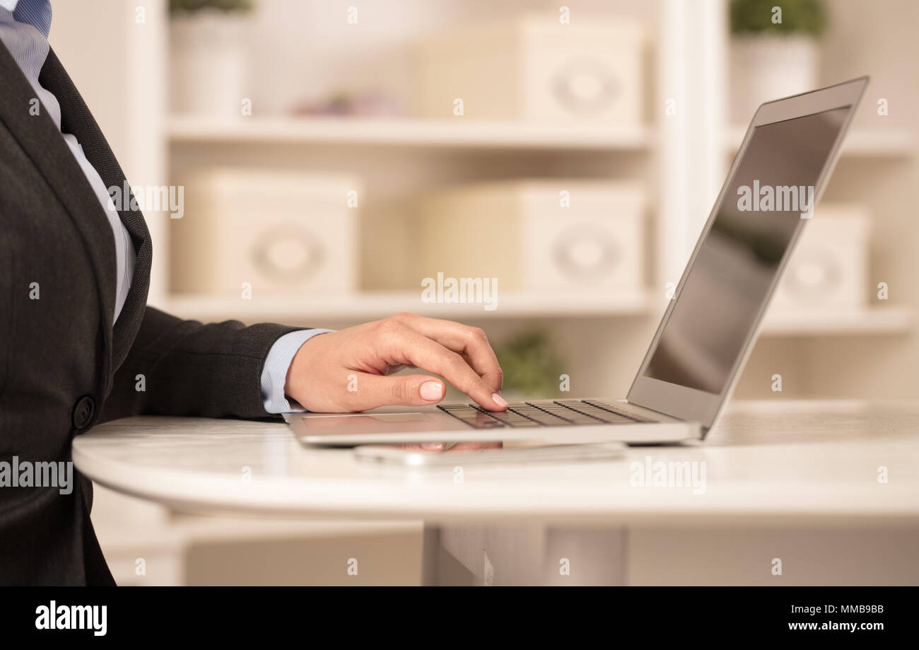 Business woman below chest working on her laptop in a cozy environment ...