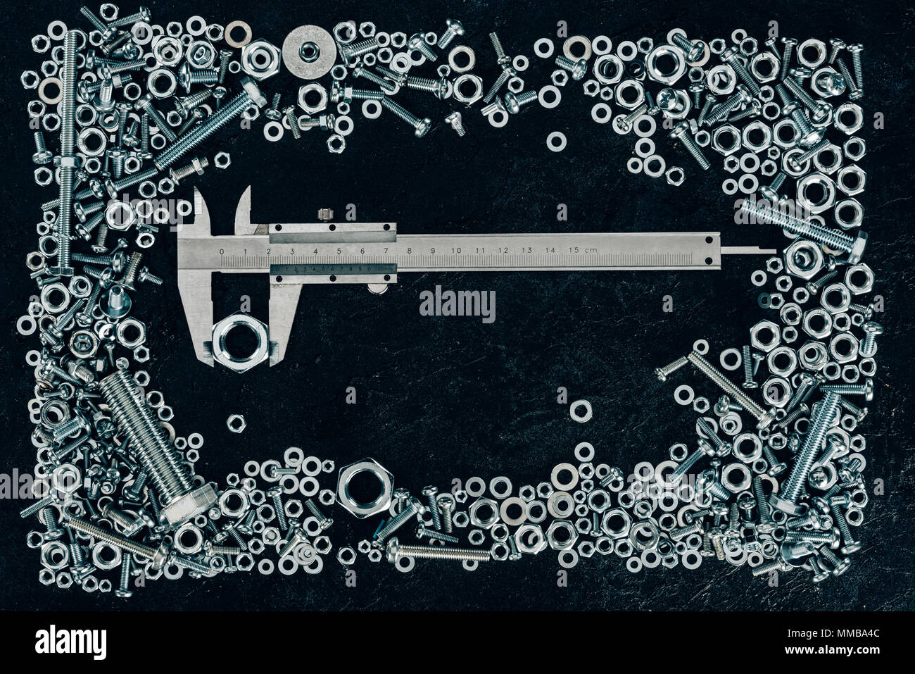 top view of metal vernier caliper, screws and clinchers on dark ...