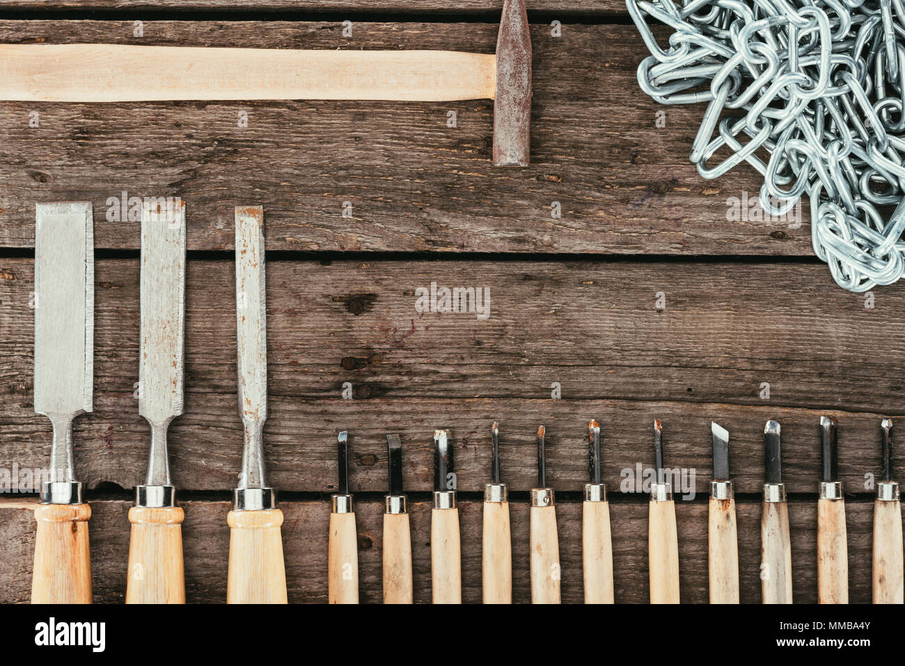flat lay with chain, hammer and chisels for woodcraft on dark wooden ...