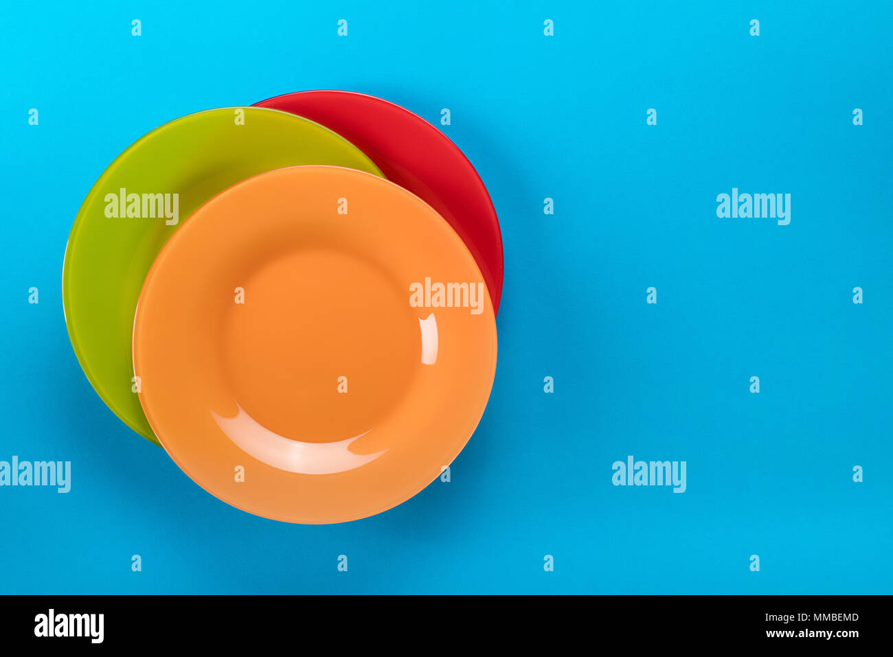 Empty bright colored plates on blue background top view with copy space ...