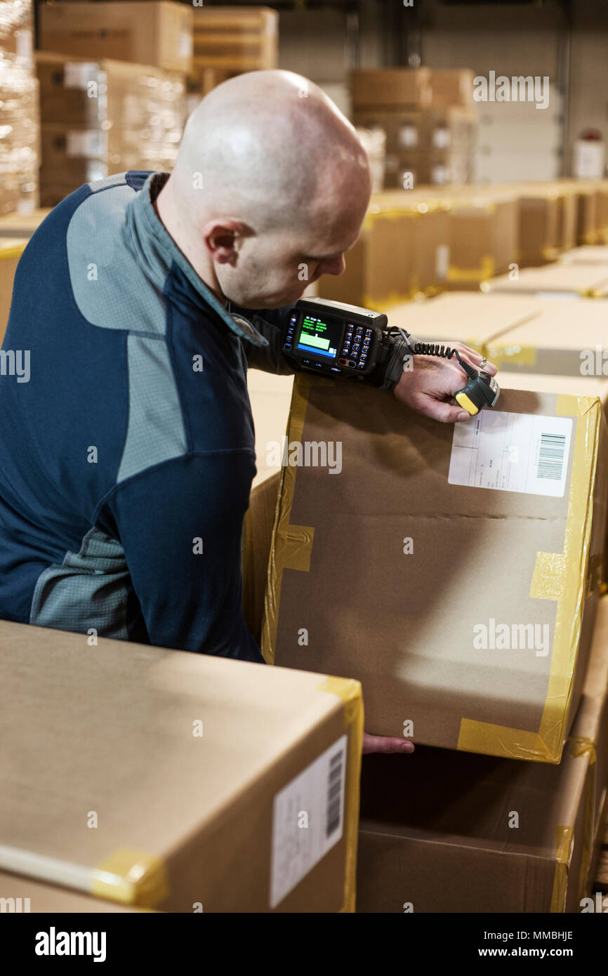 Caucasian male warehouse worker handling using a hand held bar code ...